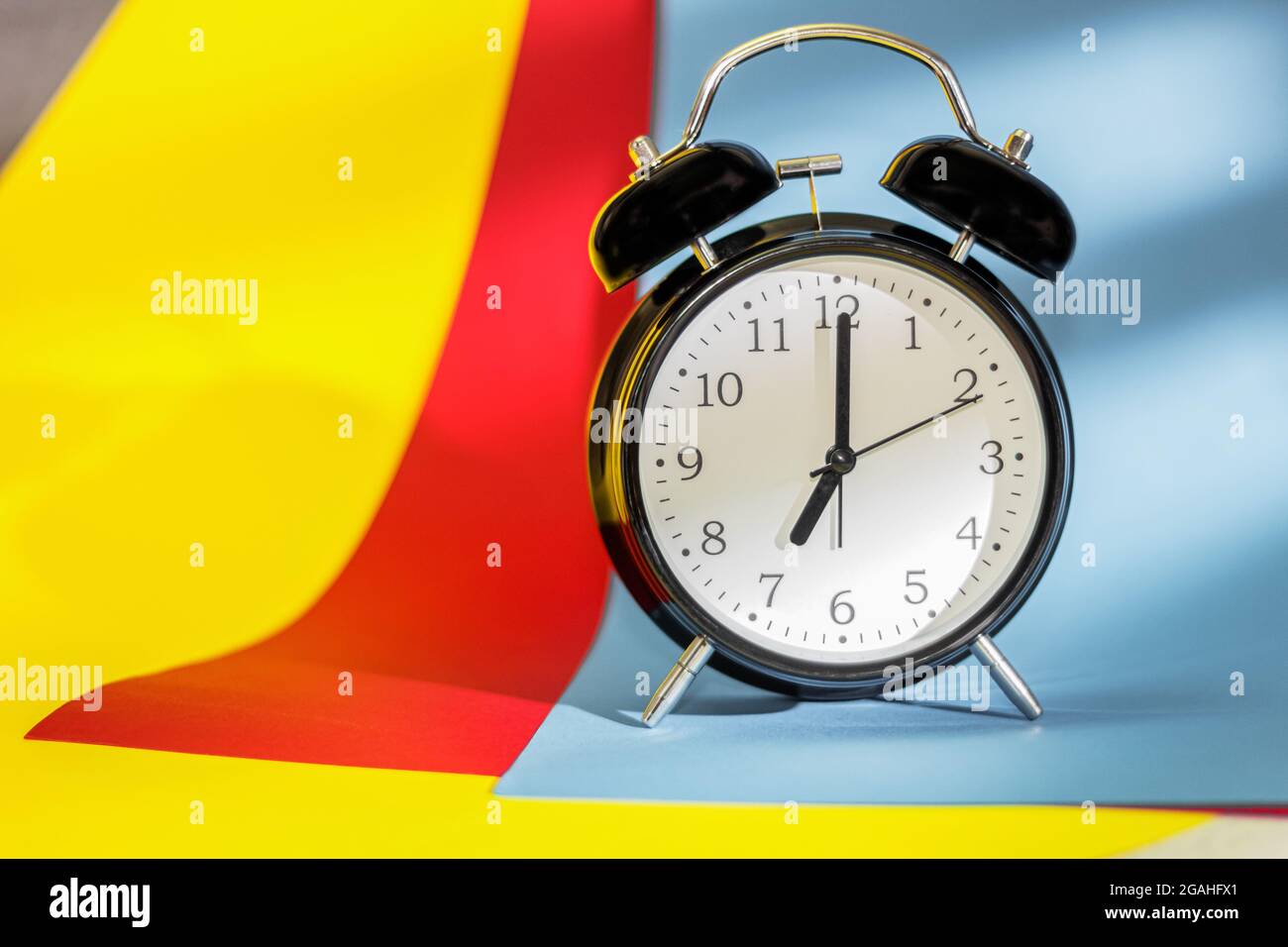 The retro alarm clock indicates 7:00 am and is illuminated by rays of ...