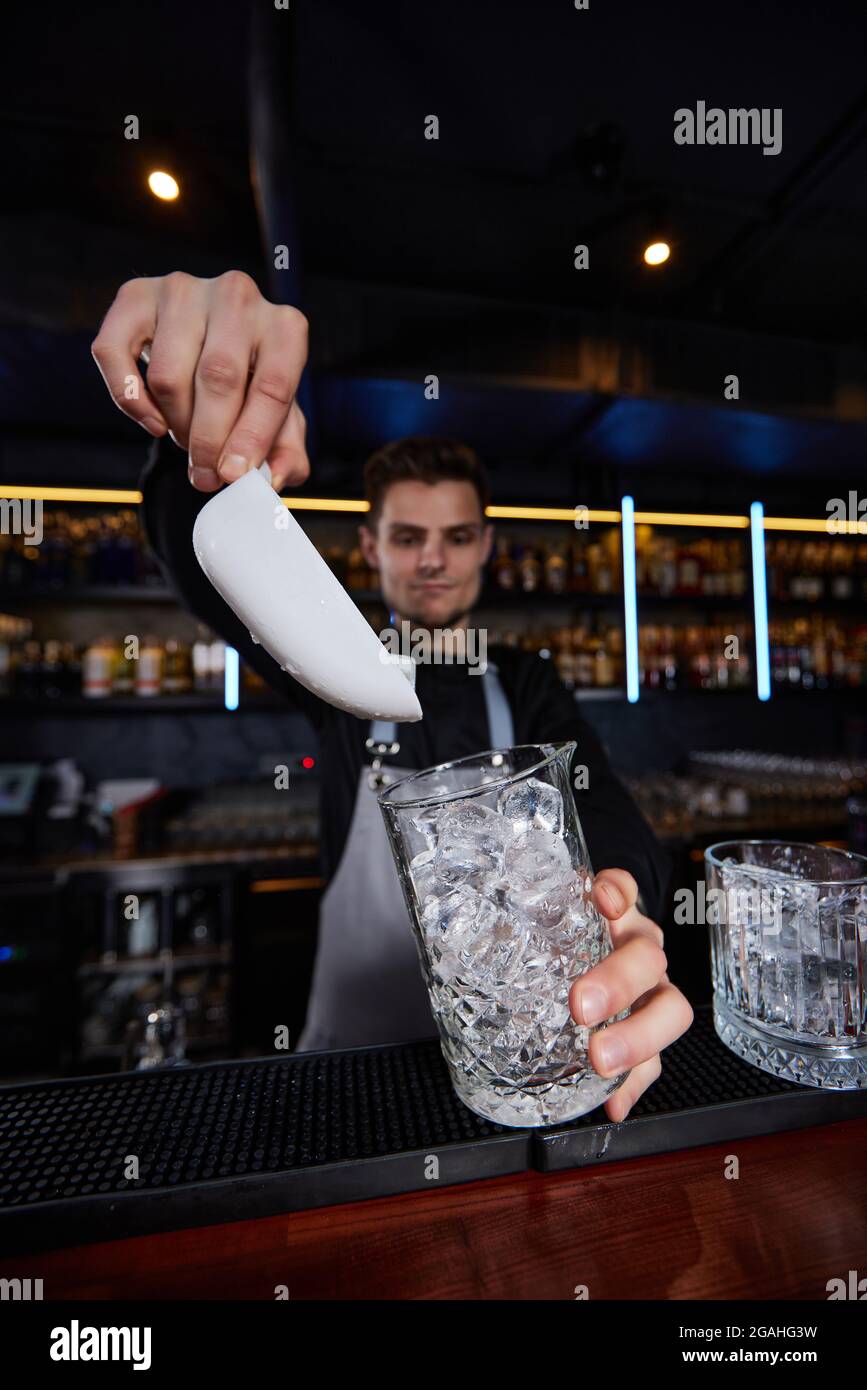Barman puts the ice cubes into a glass Stock Photo - Alamy