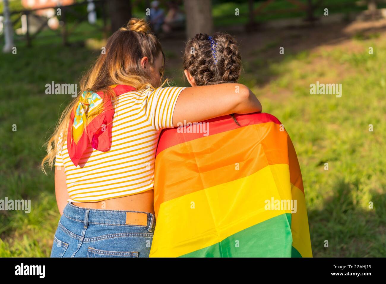 Closeup shot of two young Caucasian hugging females with LGBT pride ...