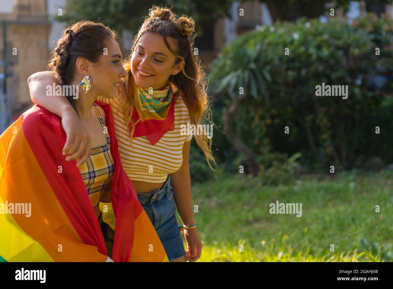 Closeup shot of two young Caucasian hugging females with LGBT pride ...