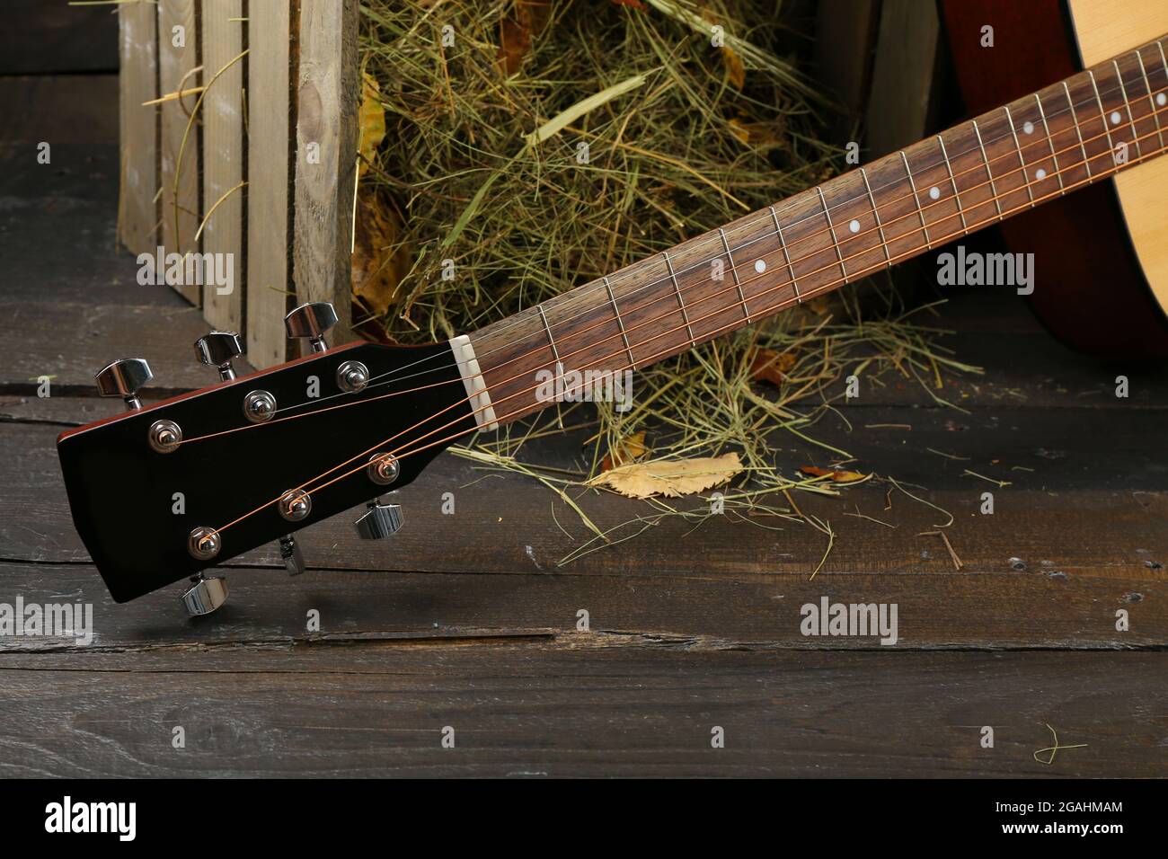 Acoustic guitar against box with hay on wooden background,, close up ...