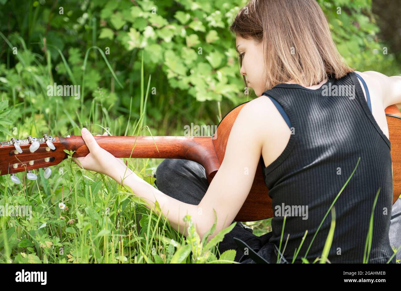 Teenager girl playing guitar in the park. Back view Stock Photo - Alamy