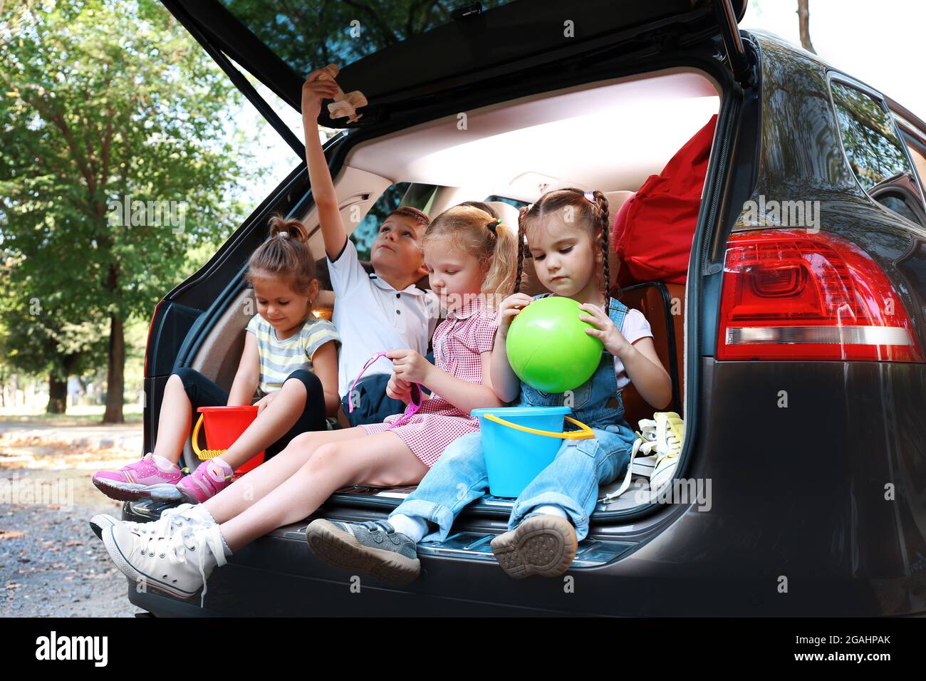 Three beautiful girls and boy sit on a car trunk and laughing Stock ...