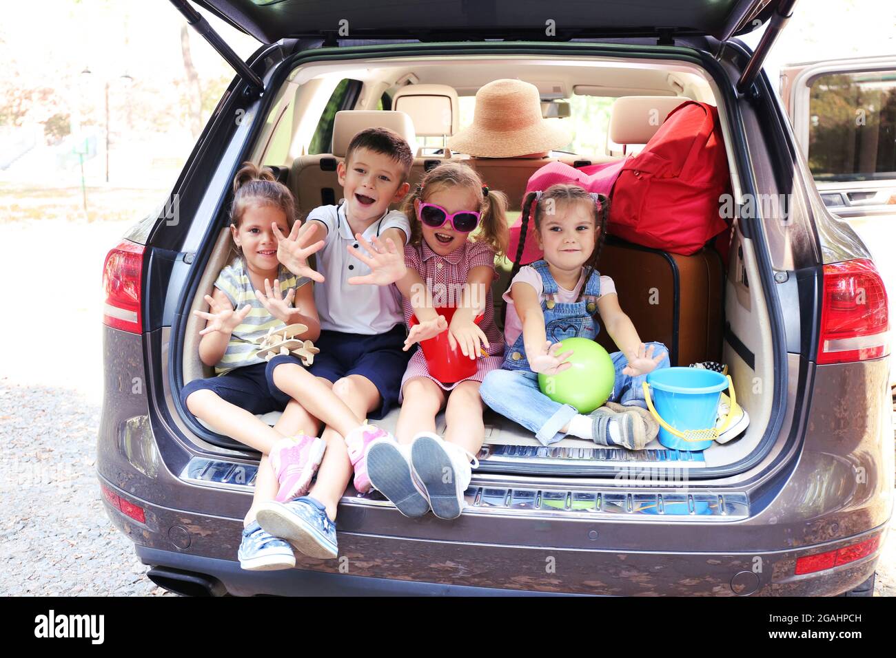 Three beautiful girls and boy sit on a car trunk and laughing Stock ...