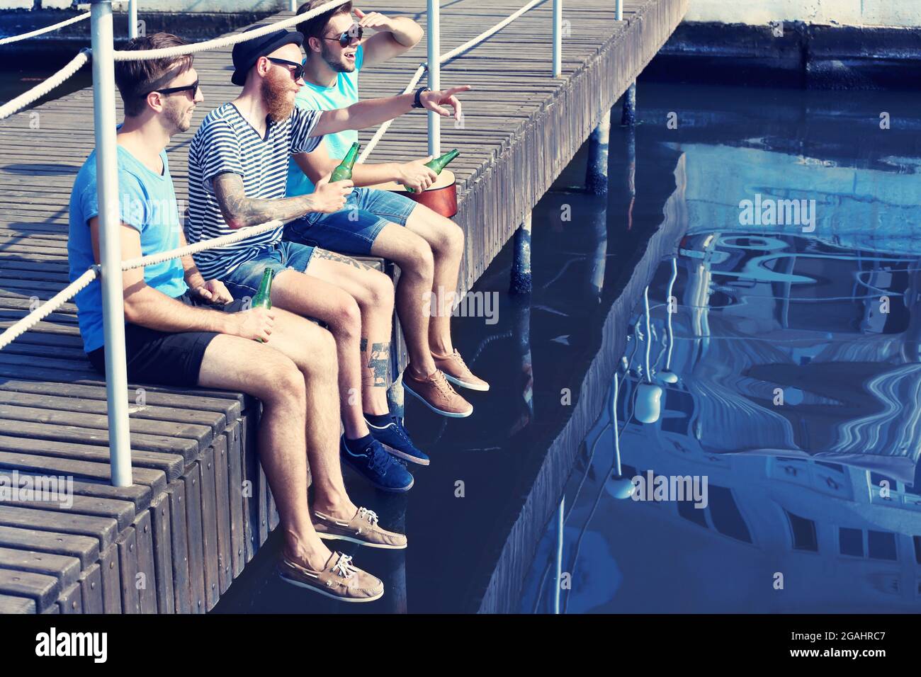 Young men sitting on the dock and talking with each other Stock Photo ...