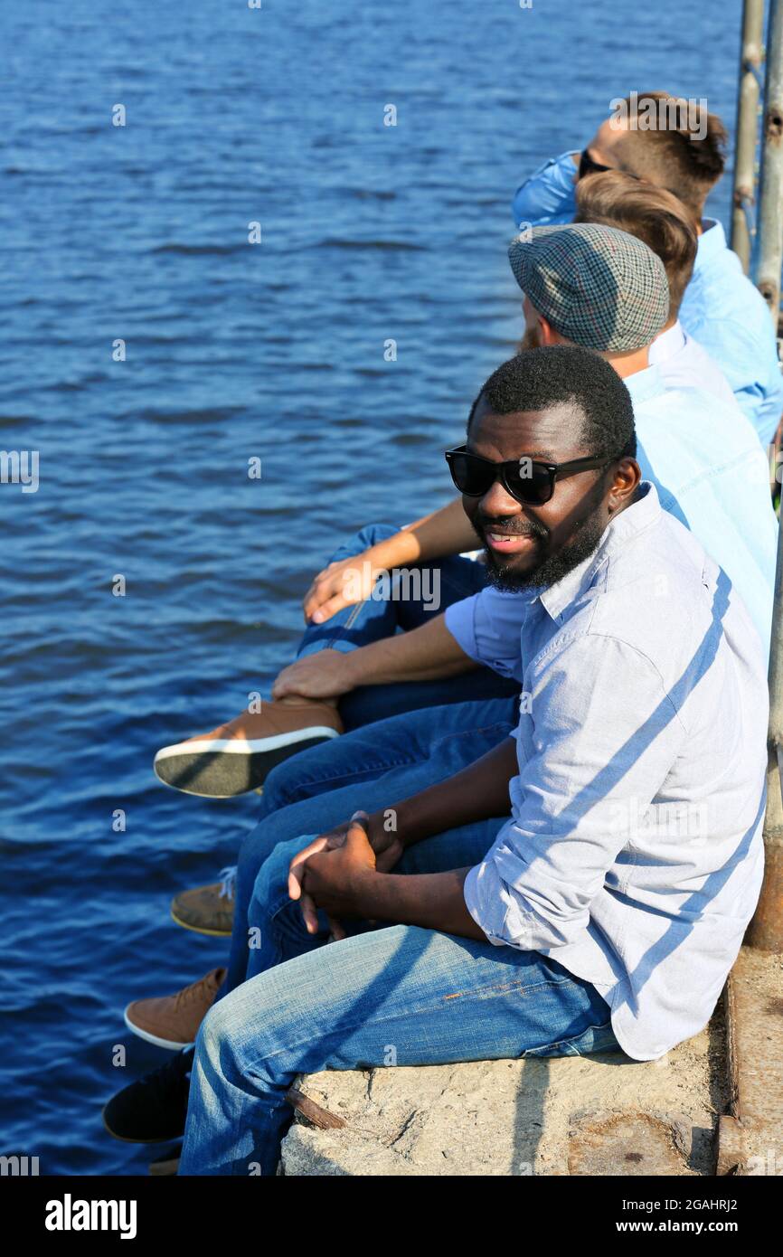 Young men relaxing on the riverside Stock Photo - Alamy