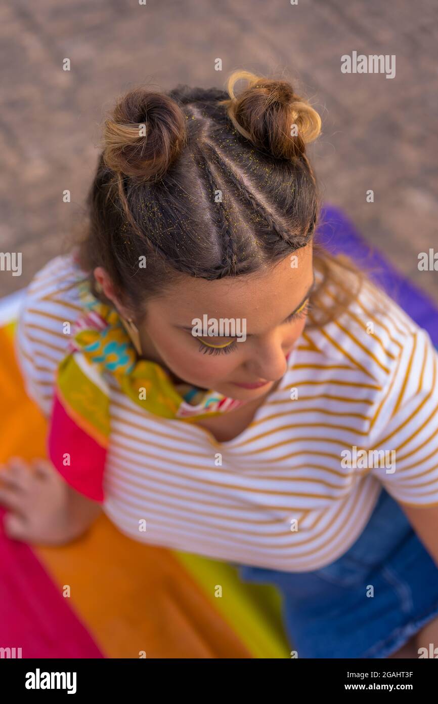 Vertical shot of a young Caucasian female sitting on LGBT pride flag ...