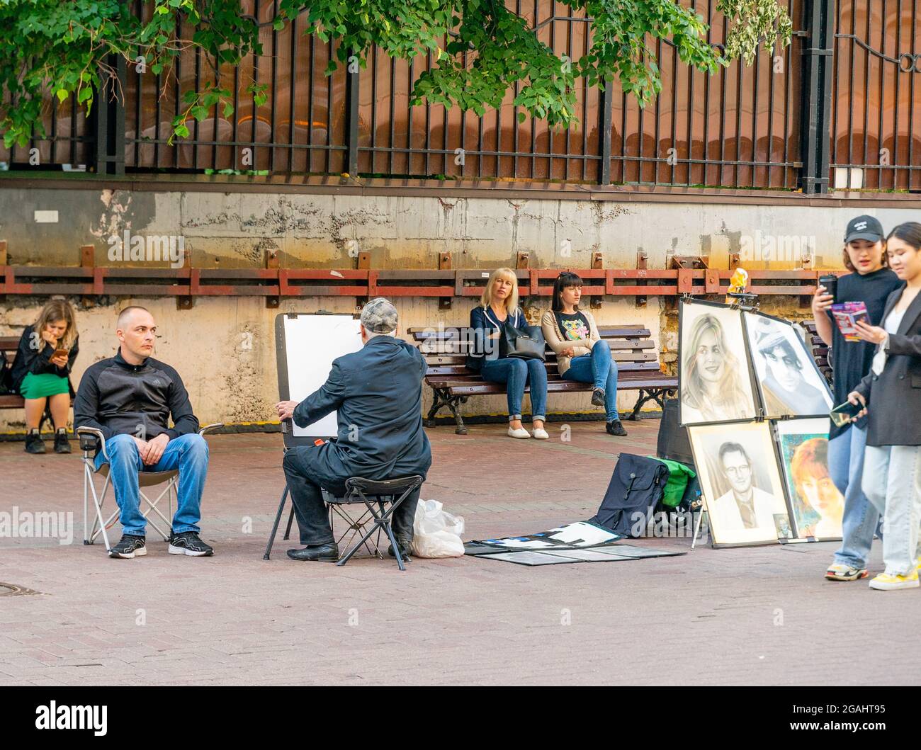 Street painter painting a man on Arbat street, famous for its street ...