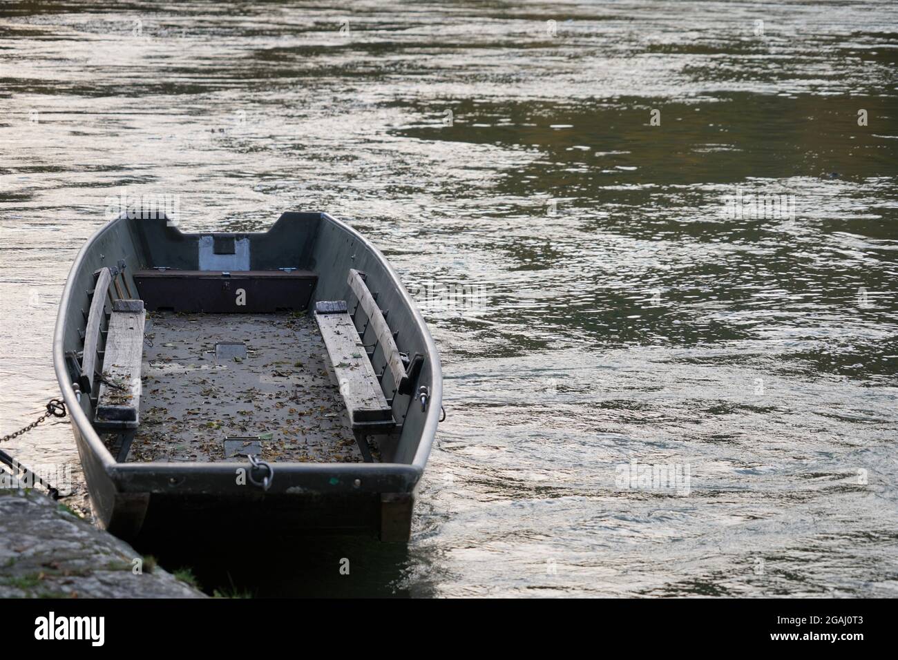 Rowing boat moored or a river bank in a strong current. Copy space is ...