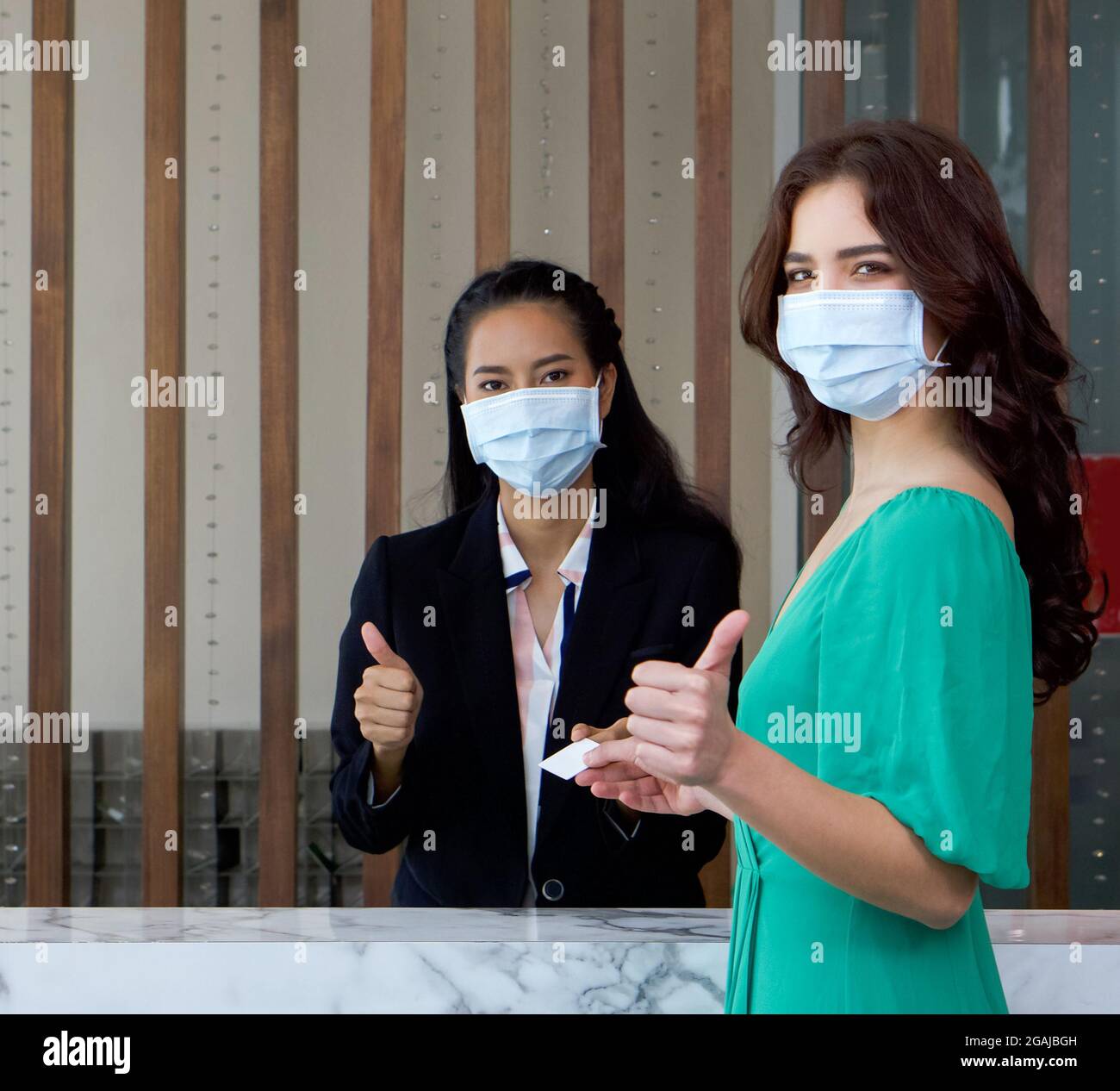 Caucasian tourist in green cloth receiving a room card from hotel ...