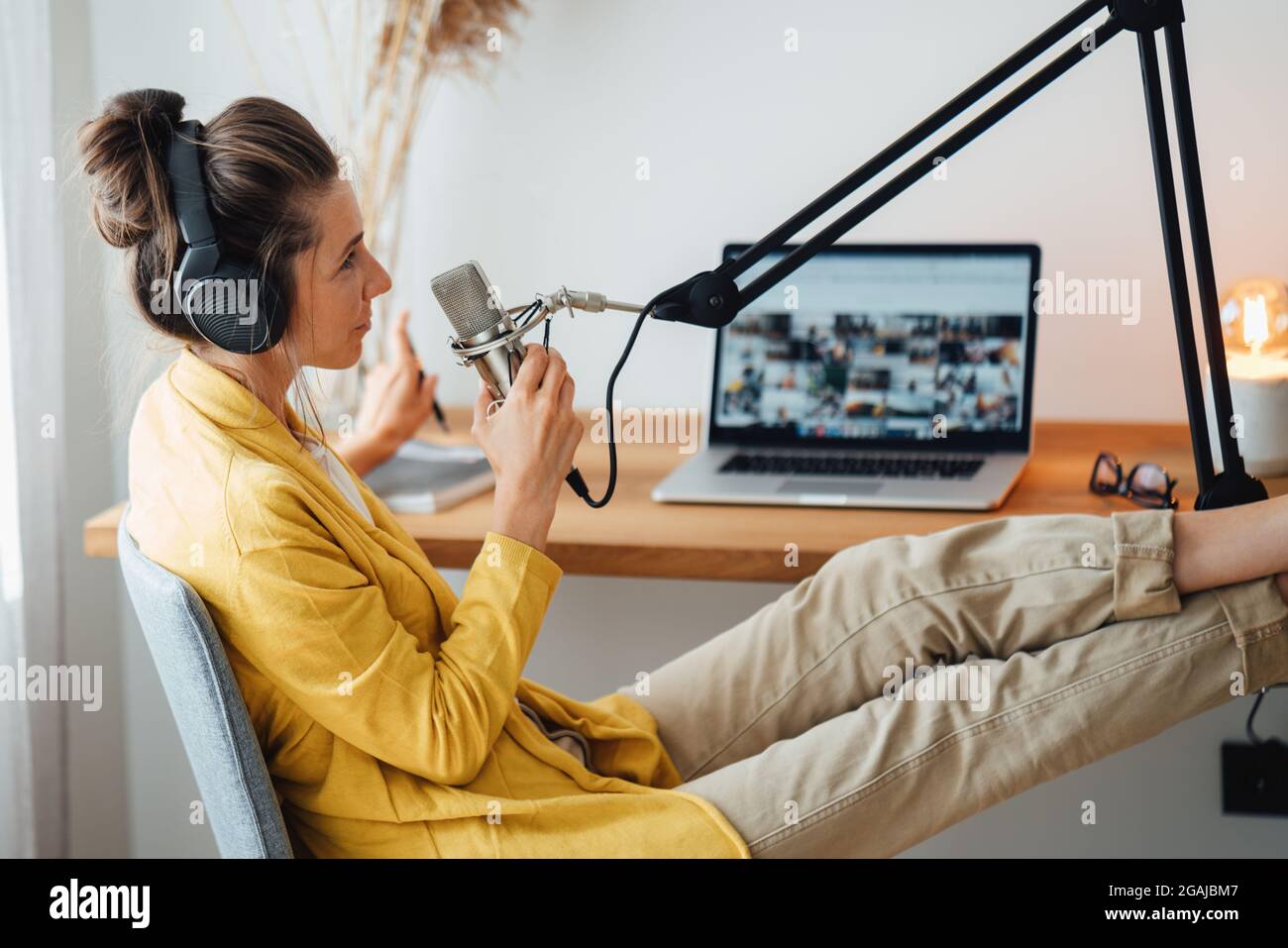 Woman sits with his feet up on his desk and recording live podcast ...