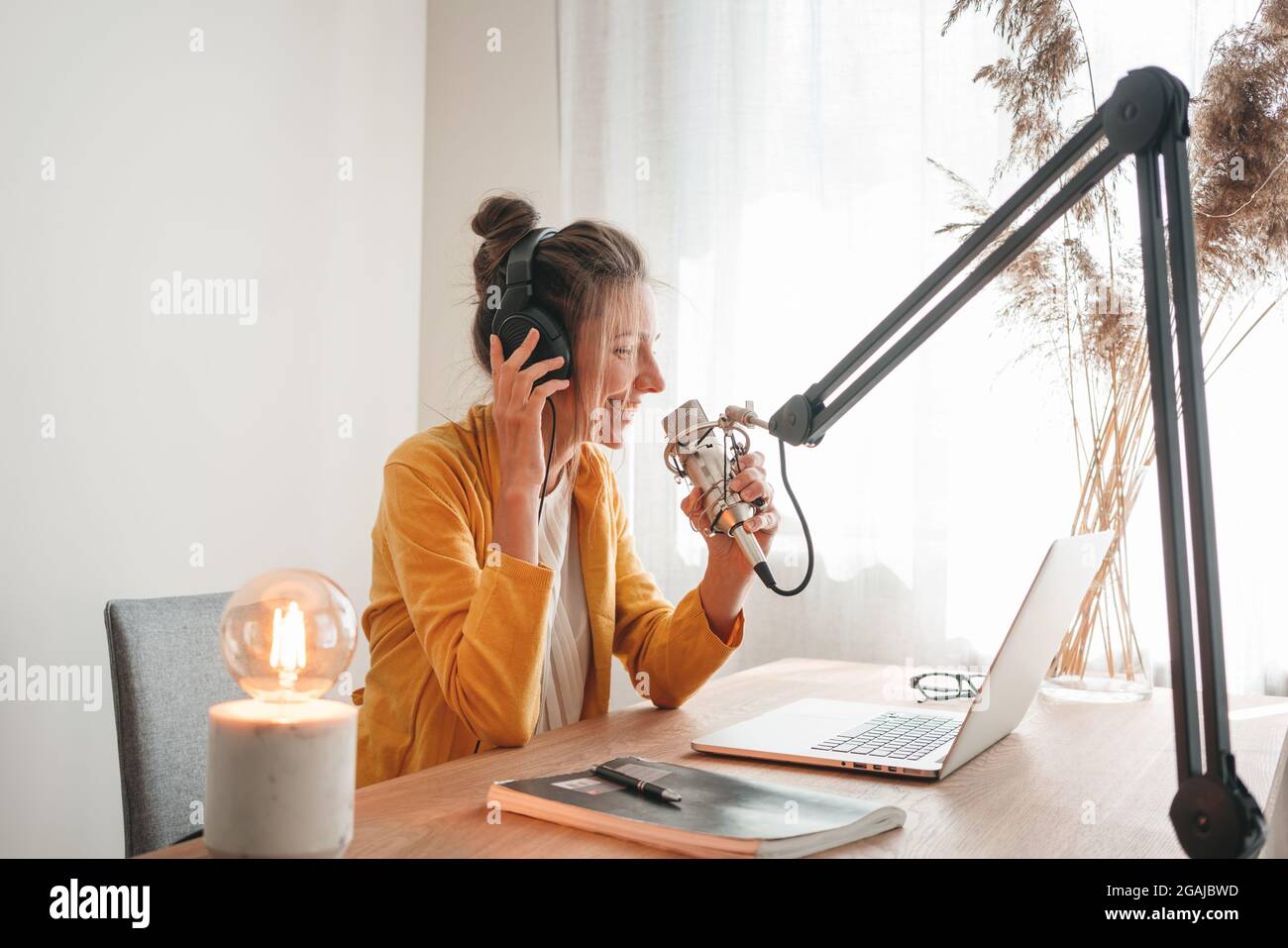 Female podcaster recording her podcast using microphone and laptop at ...