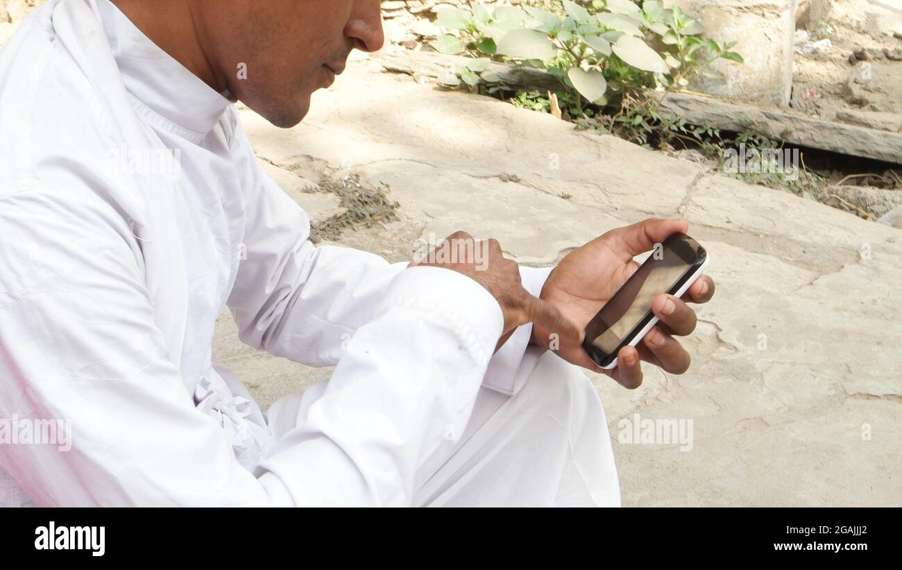 Indian male sitting on the rock and scrolling on a smartphone Stock ...