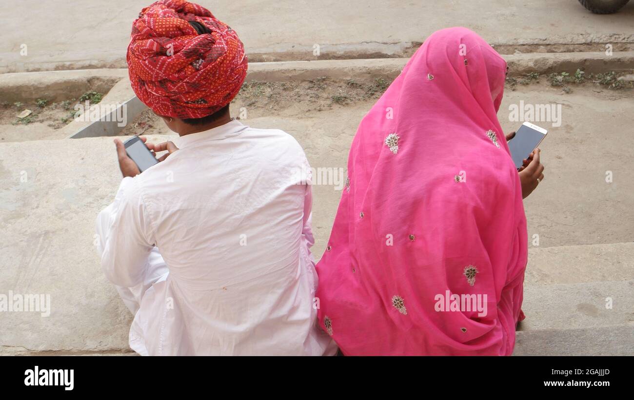 Back view of an Indian male and a female sitting and scrolling on their ...