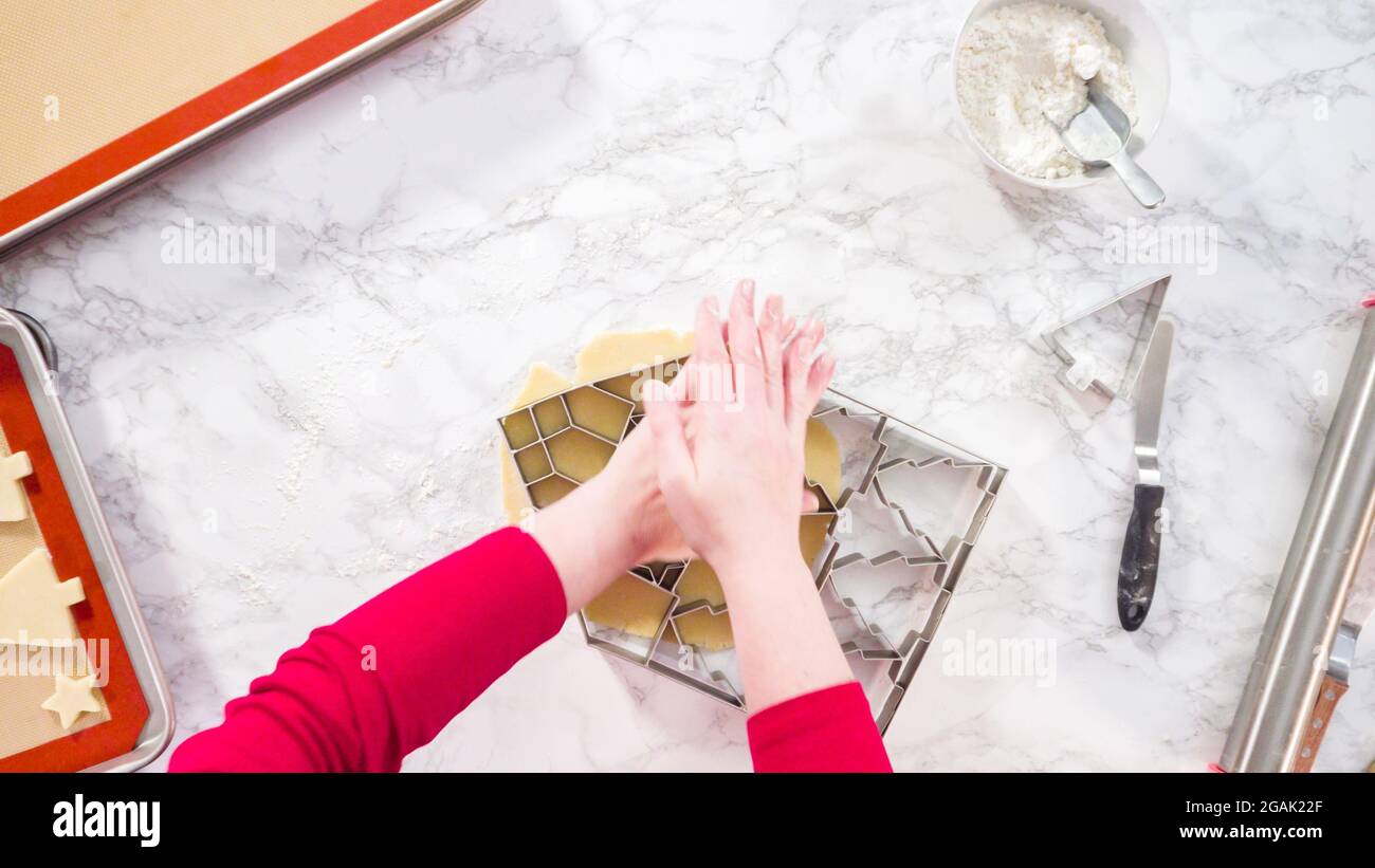 Flat lay. Cutting out sugar cookies with giant Christmas cookie cutter ...