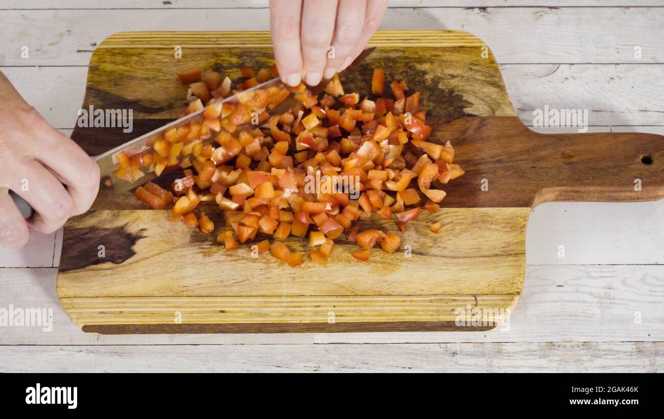 Mincing organic red bell peppers on a wood cutting board Stock Photo ...