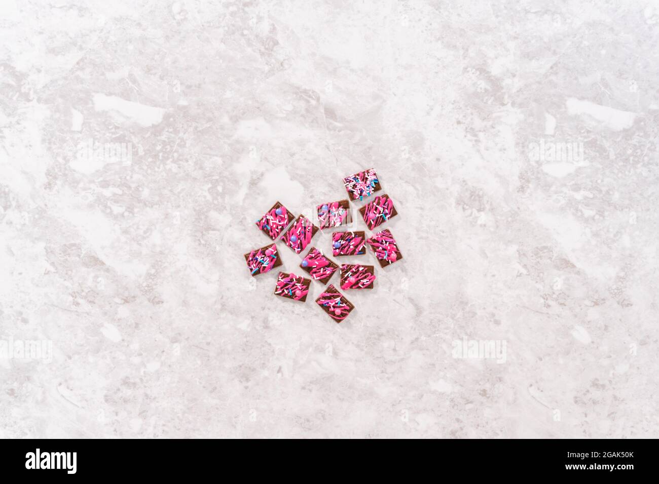 Flat lay. Gourmet dark mini chocolates with drizzled pink chocolate and ...