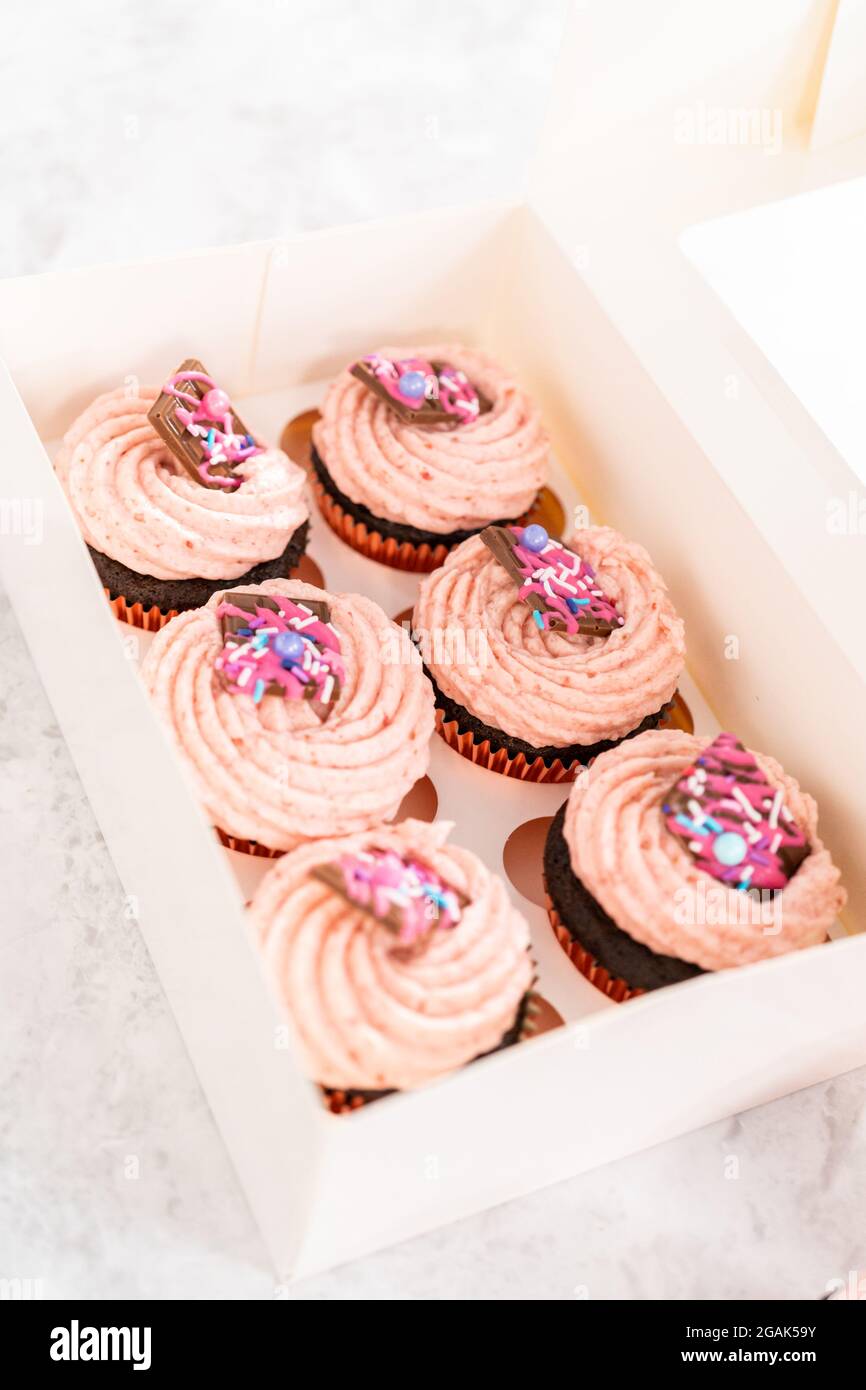 Packaging freshly baked chocolate strawberry cupcakes garnished with ...