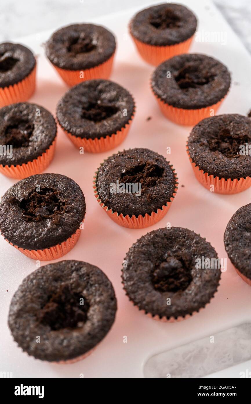 Filling freshly baked chocolate cupcakes with strawberry filling Stock ...