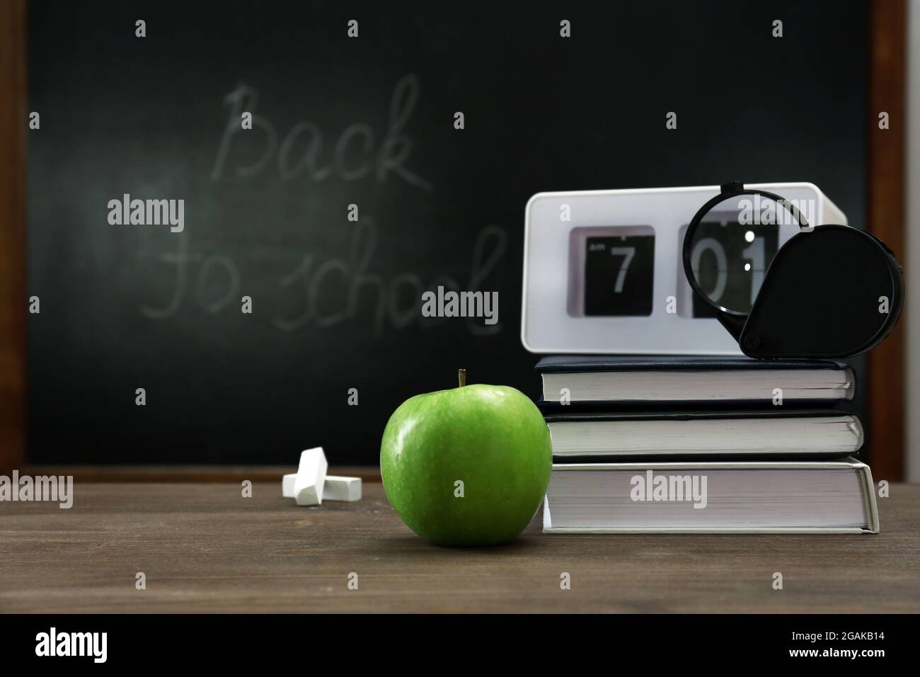Apple, books, clock and magnifier on desk background Stock Photo - Alamy