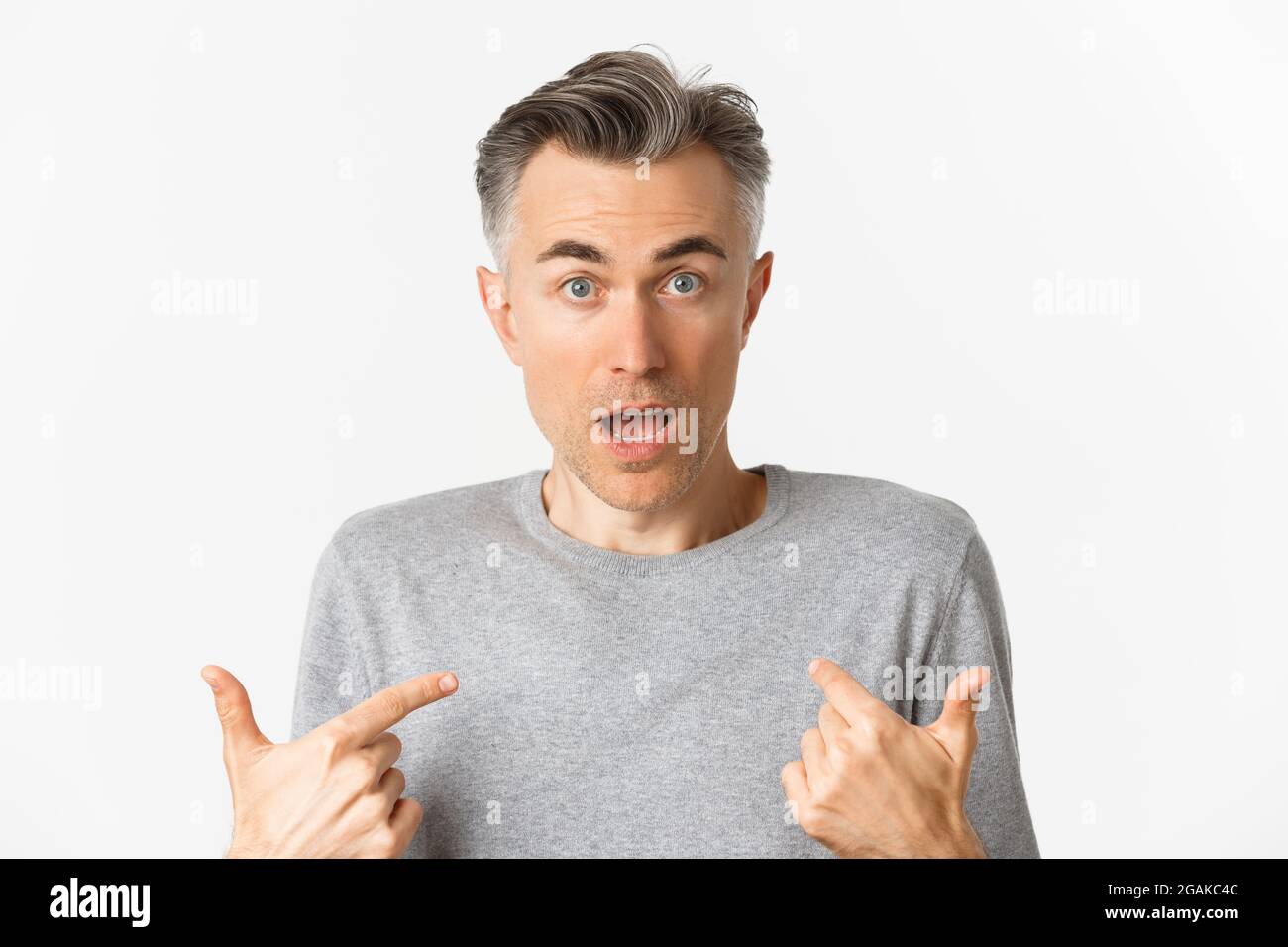 Close-up of confused middle-aged man, pointing at himself and gasping ...