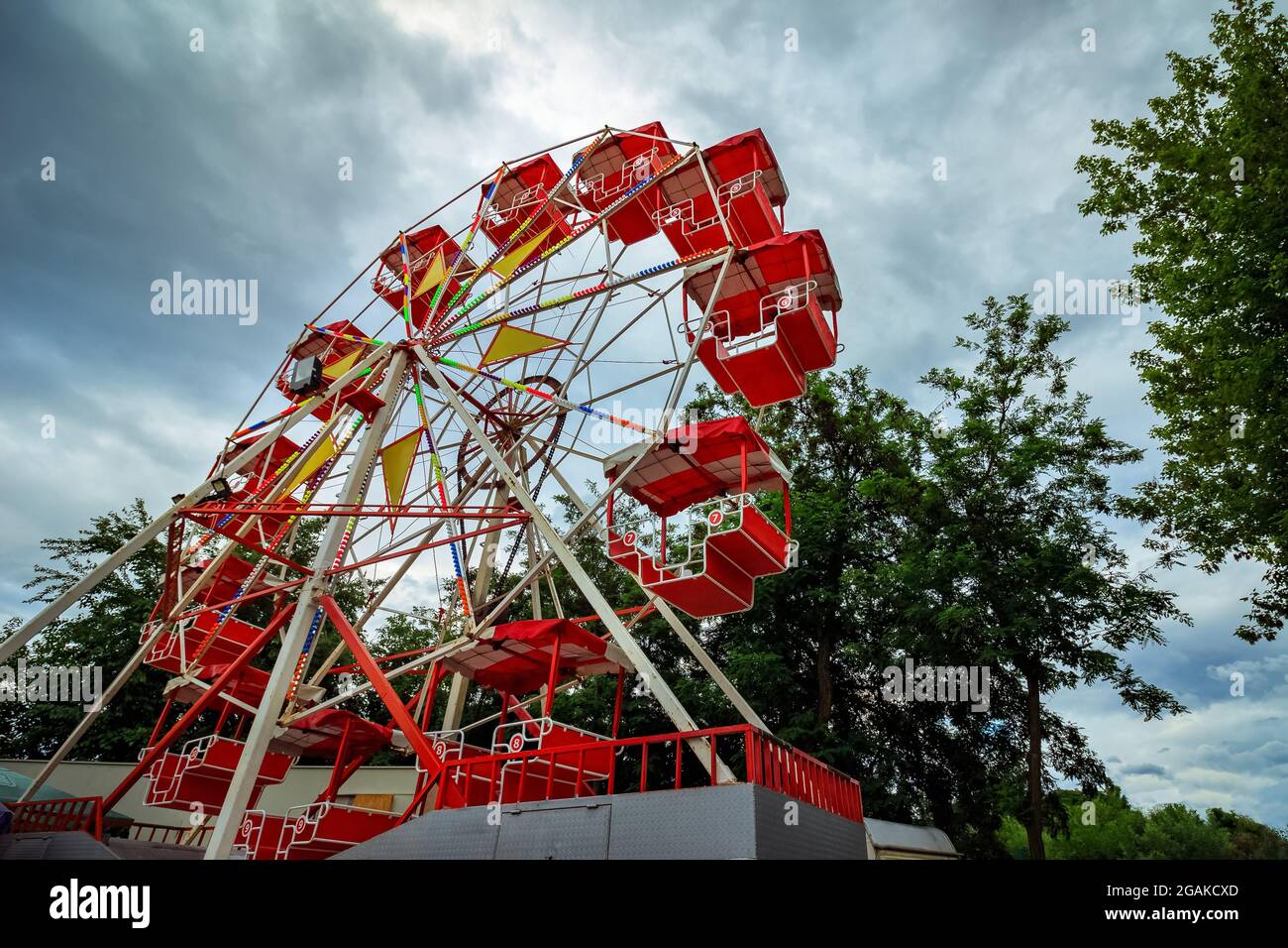 Empty red Ferris wheel on cloudy sky background Stock Photo - Alamy