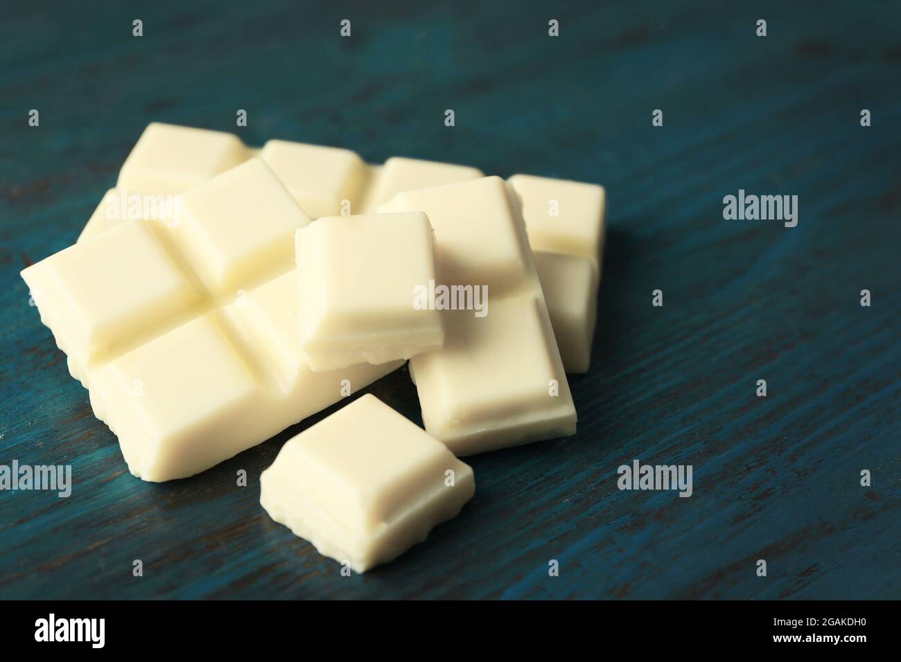 White chocolate pieces on color wooden background Stock Photo - Alamy