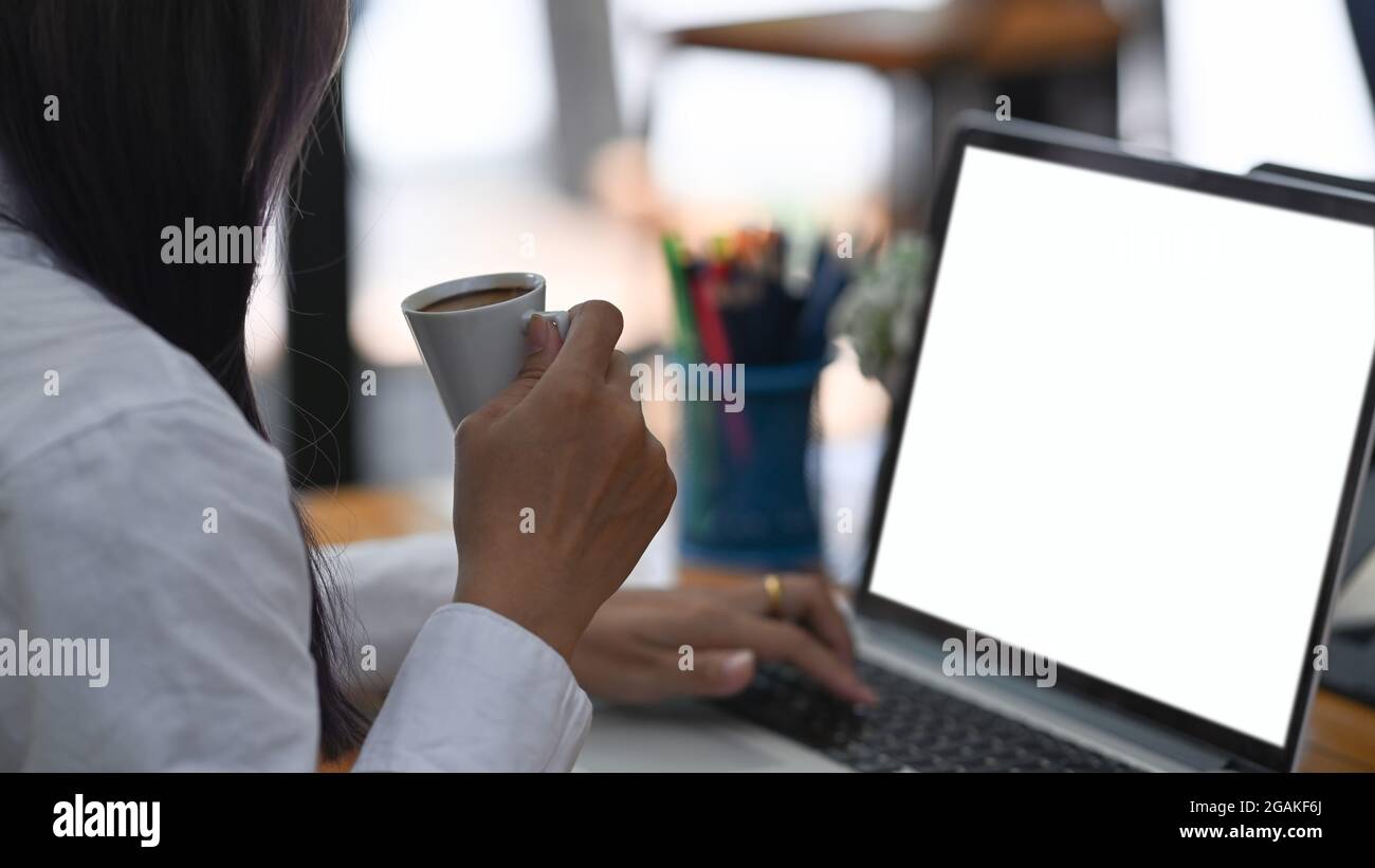 Cropped shot female office worker drinking coffee and working with ...