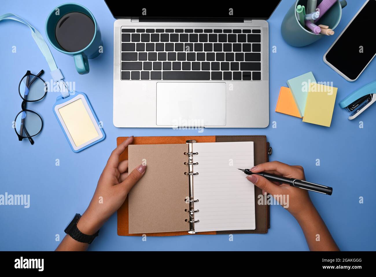 Overhead shot female office worker writing information on notebook ...