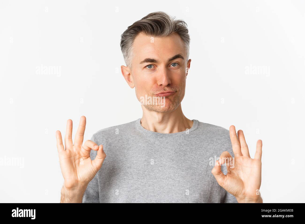 Close-up of satisfied middle-aged man in gray sweater, showing okay ...