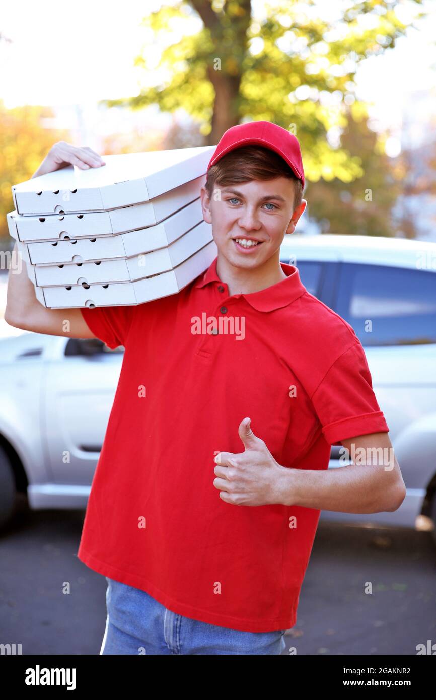 Pizza delivery boy holding boxes with pizza near car Stock Photo - Alamy