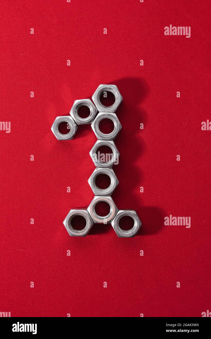 number one, made with steel nuts on red fabric background Stock Photo ...