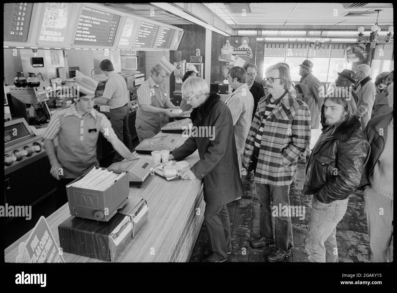 Employees behind the counter serving a line of luncheon customers at ...