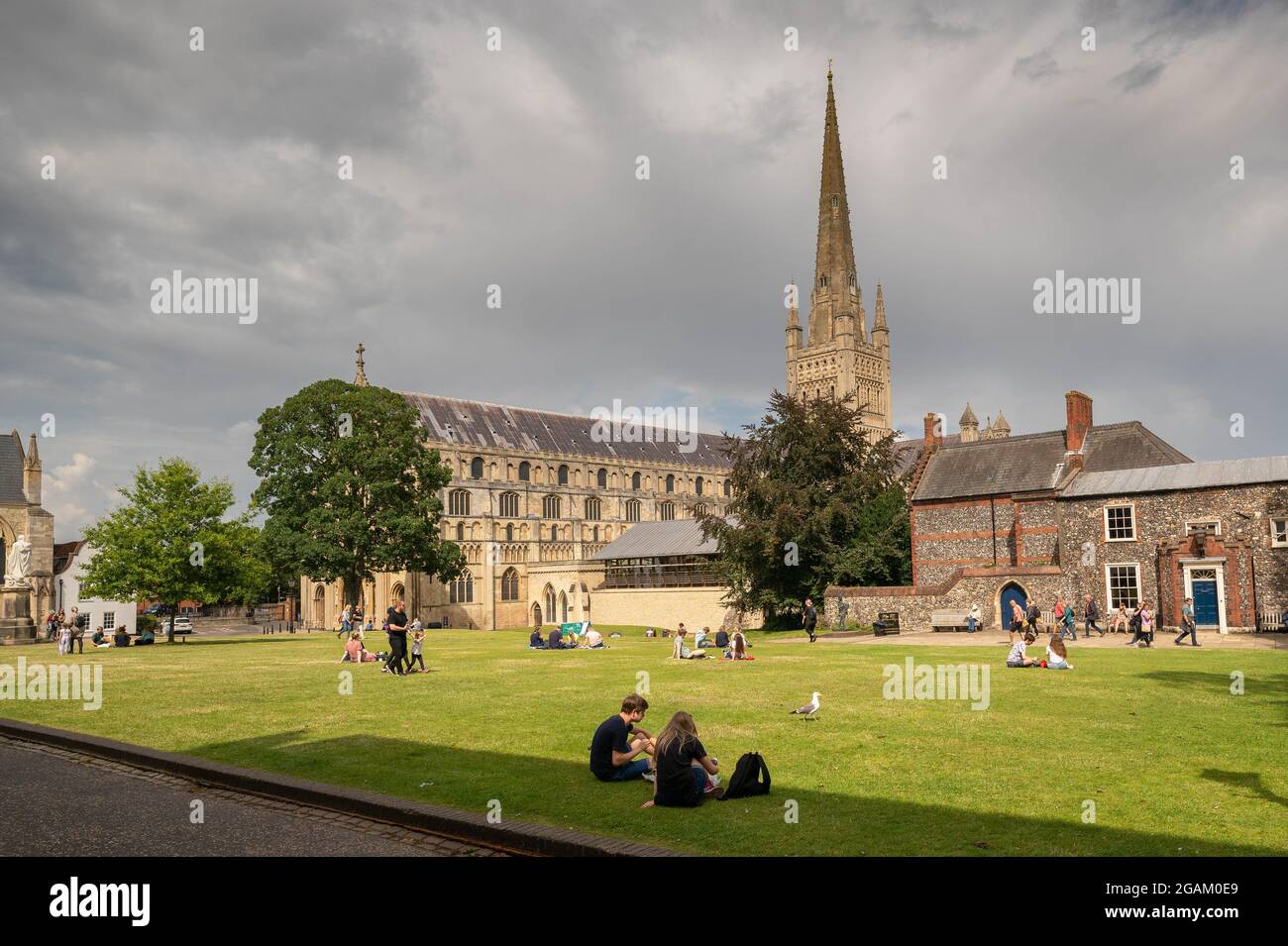 A view of Norwich cathedral and its grounds with people sitting eating ...
