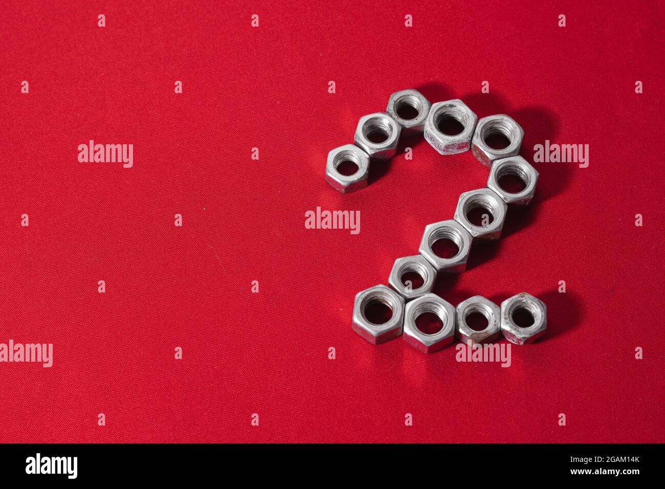 number two, made with steel nuts on red fabric background Stock Photo ...