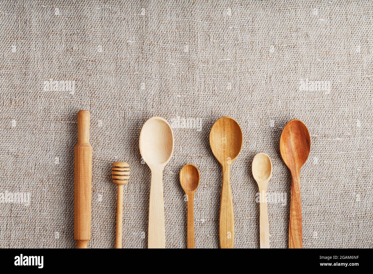 Craft spoons made from different types of wood lie in a row on a hemp ...