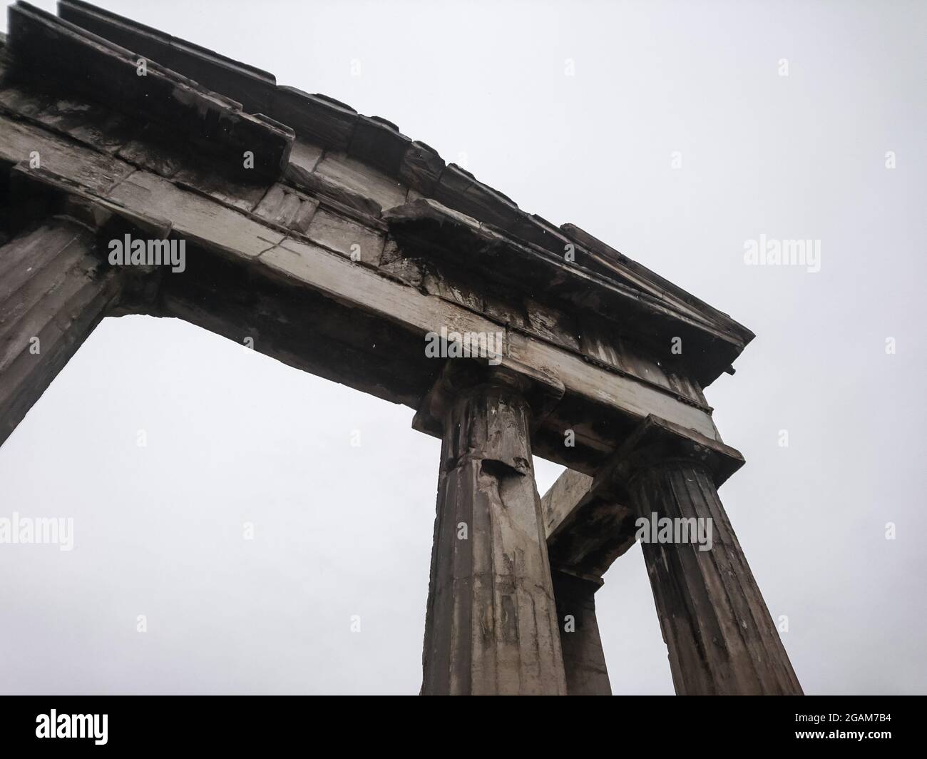 Ancient marble arch gate colonnade monument on grey sky in old Athens ...