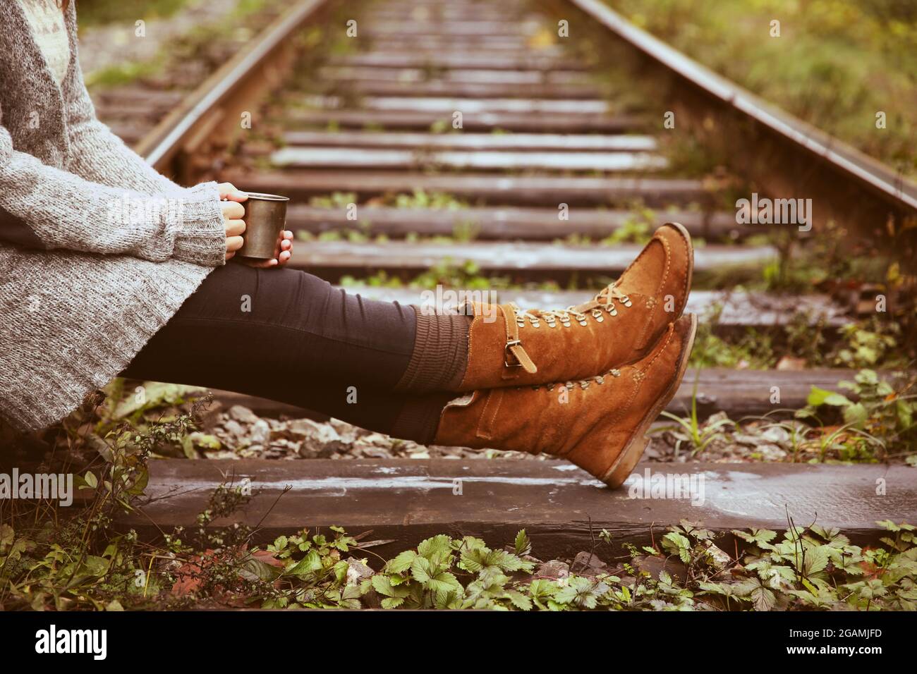 Young woman sitting on rail track Stock Photo - Alamy