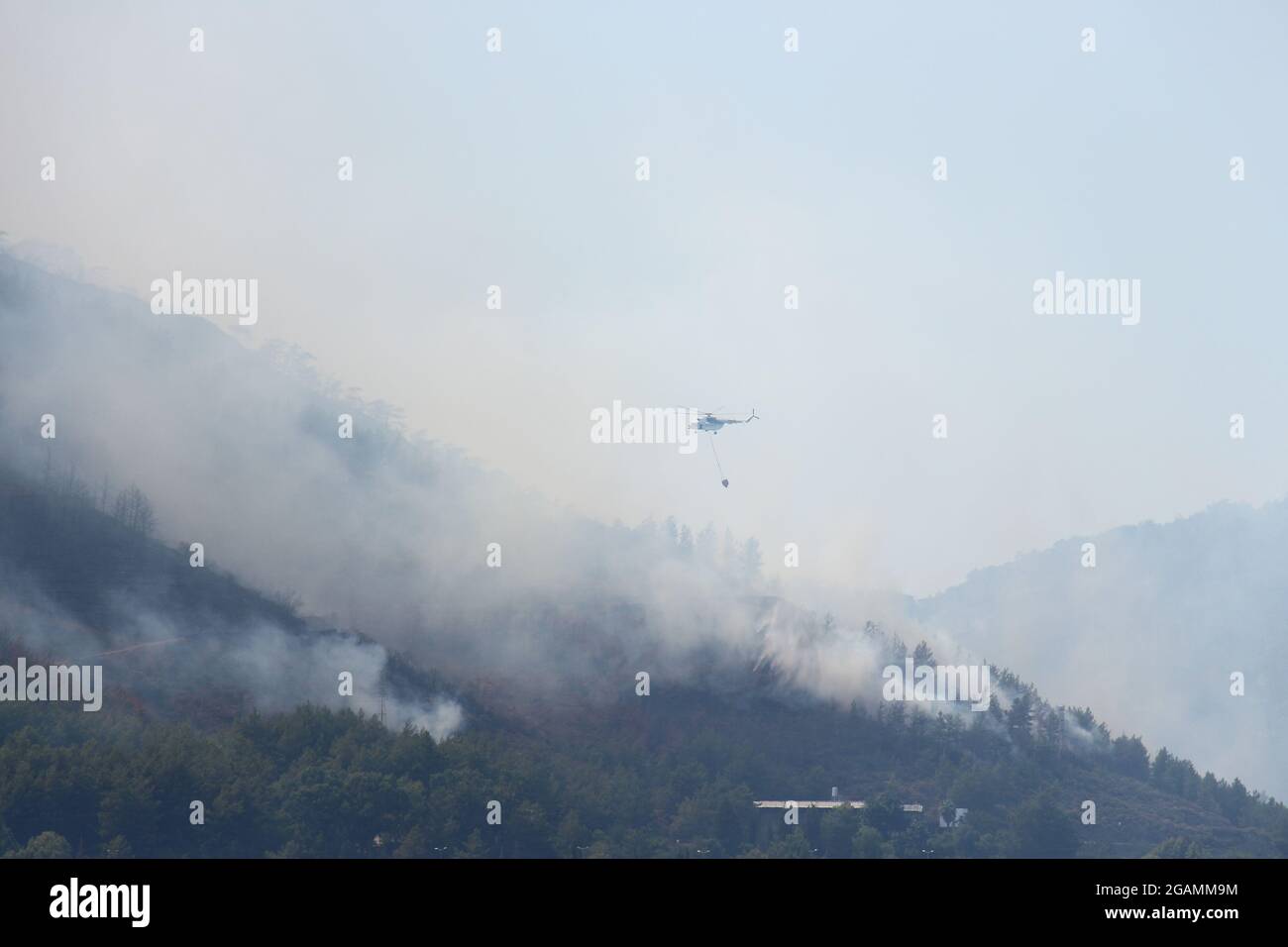 A helicopter flies through smoke rising from a forest fire in Marmaris ...