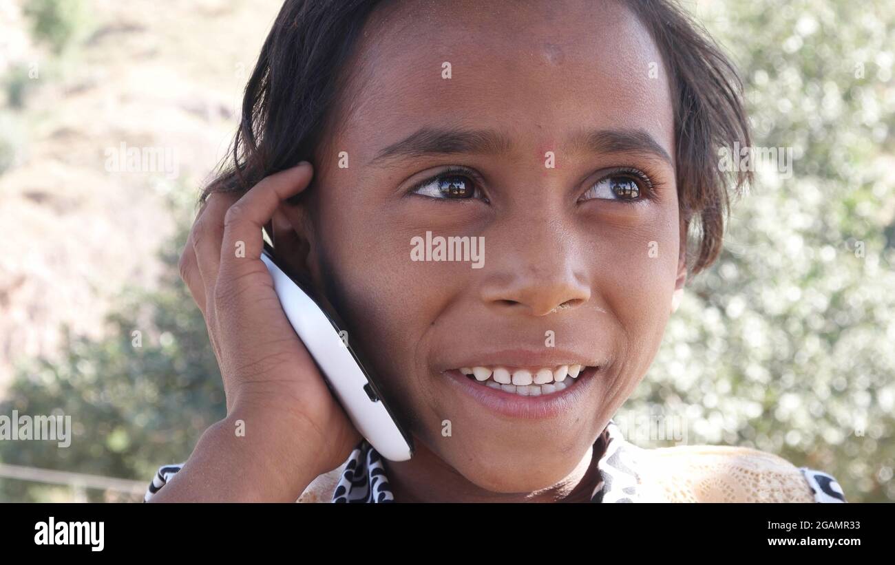 Closeup shot of an Indian female kid talking on the phone on hills ...