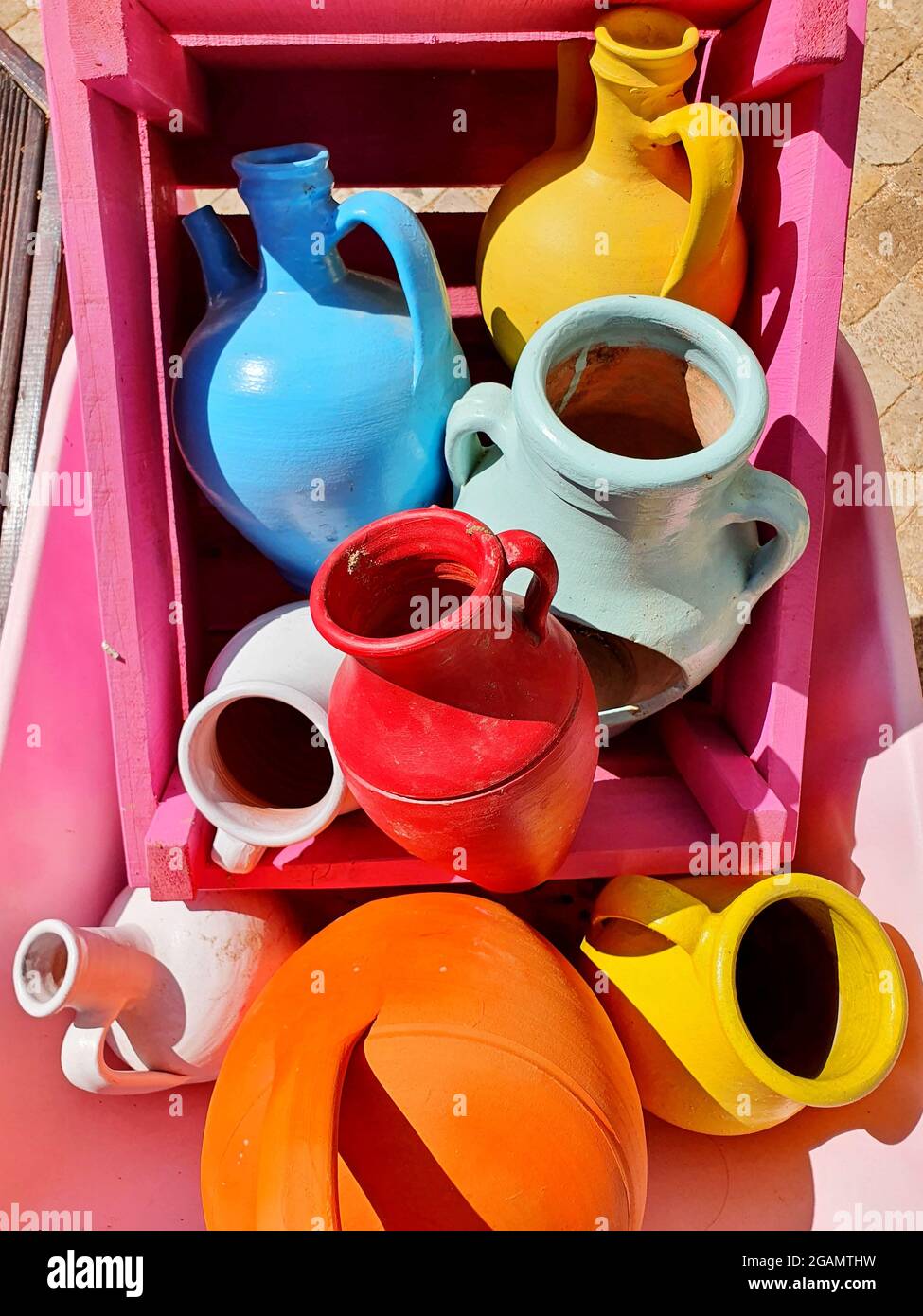 Several colorful jugs in a wheelbarrow. The jugs are made of clay and ...