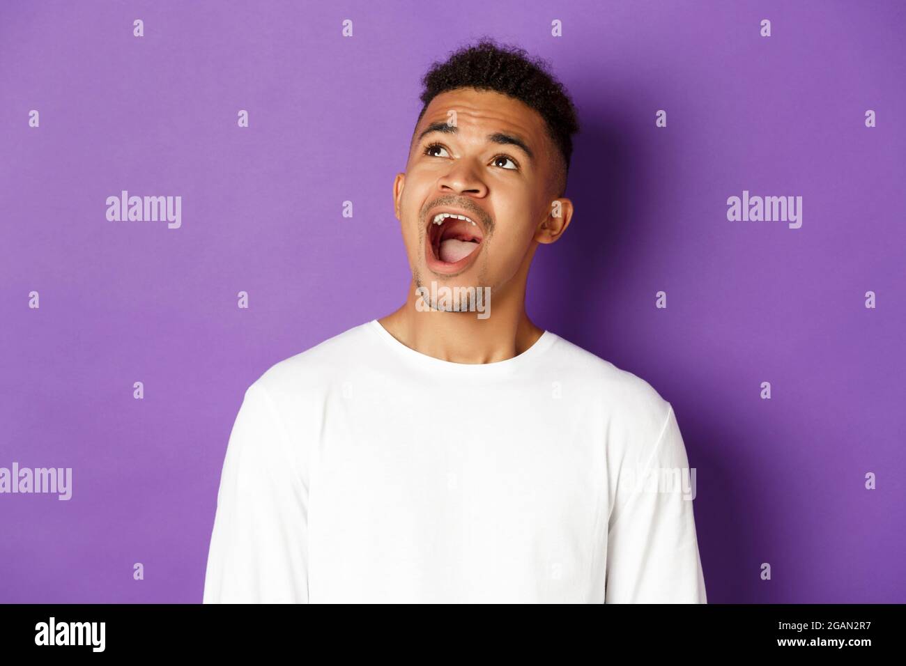 Close-up of amazed african-american young man, open mouth and saying ...