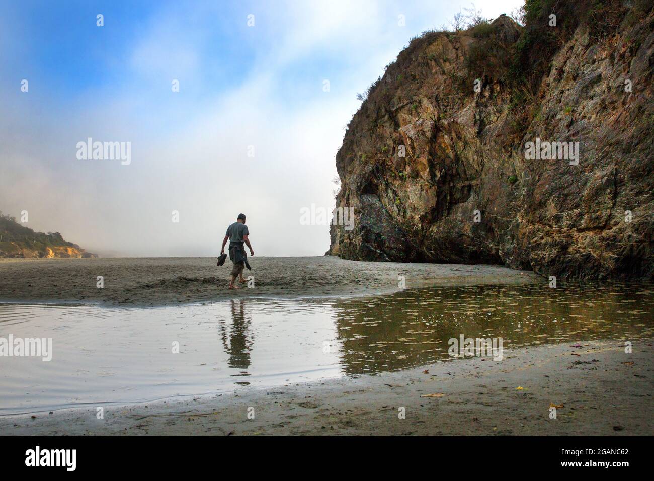 Man walking alone across a body of water on the California coast ...