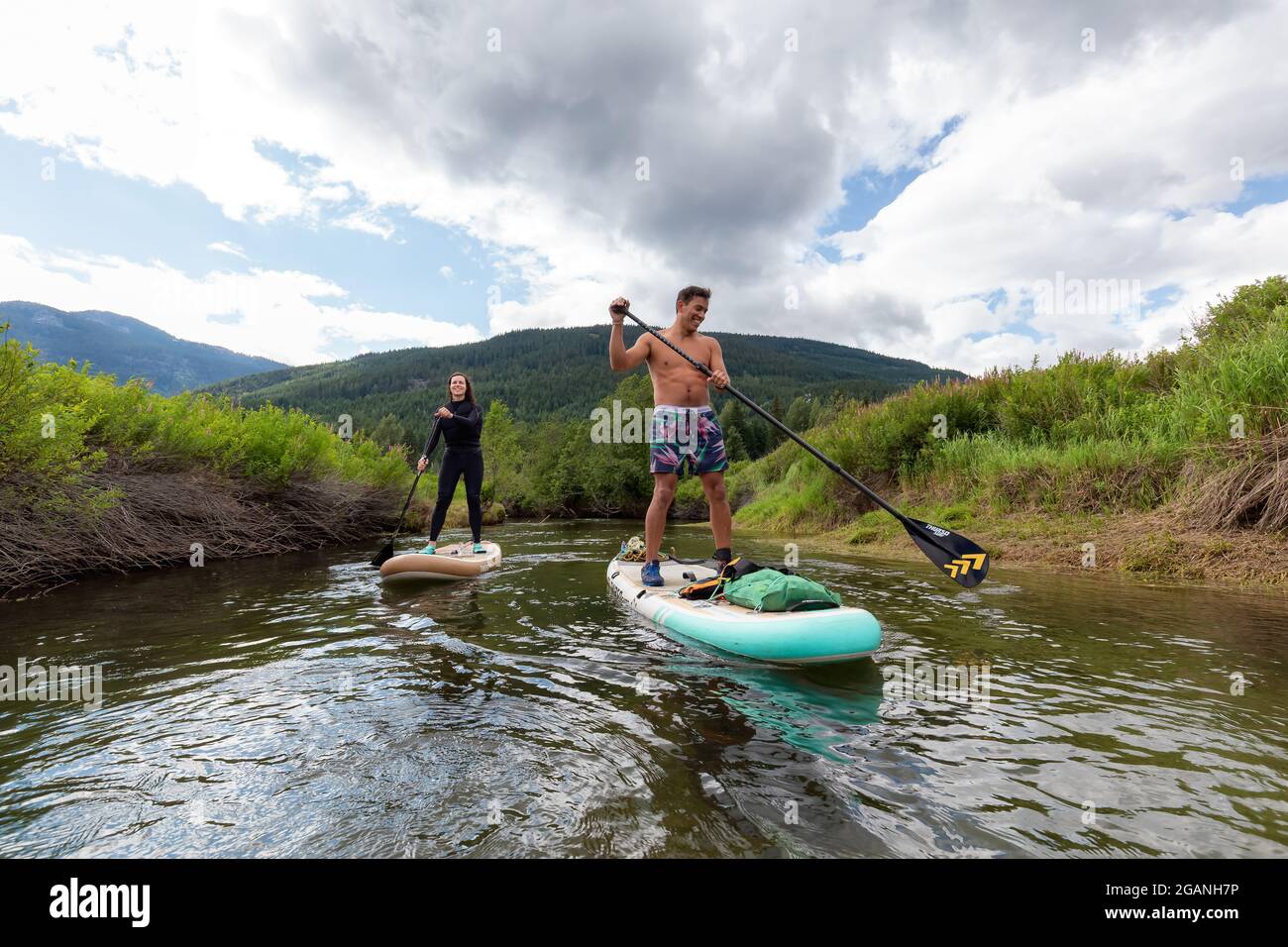 Adventurous people paddle boarding in a river Stock Photo - Alamy