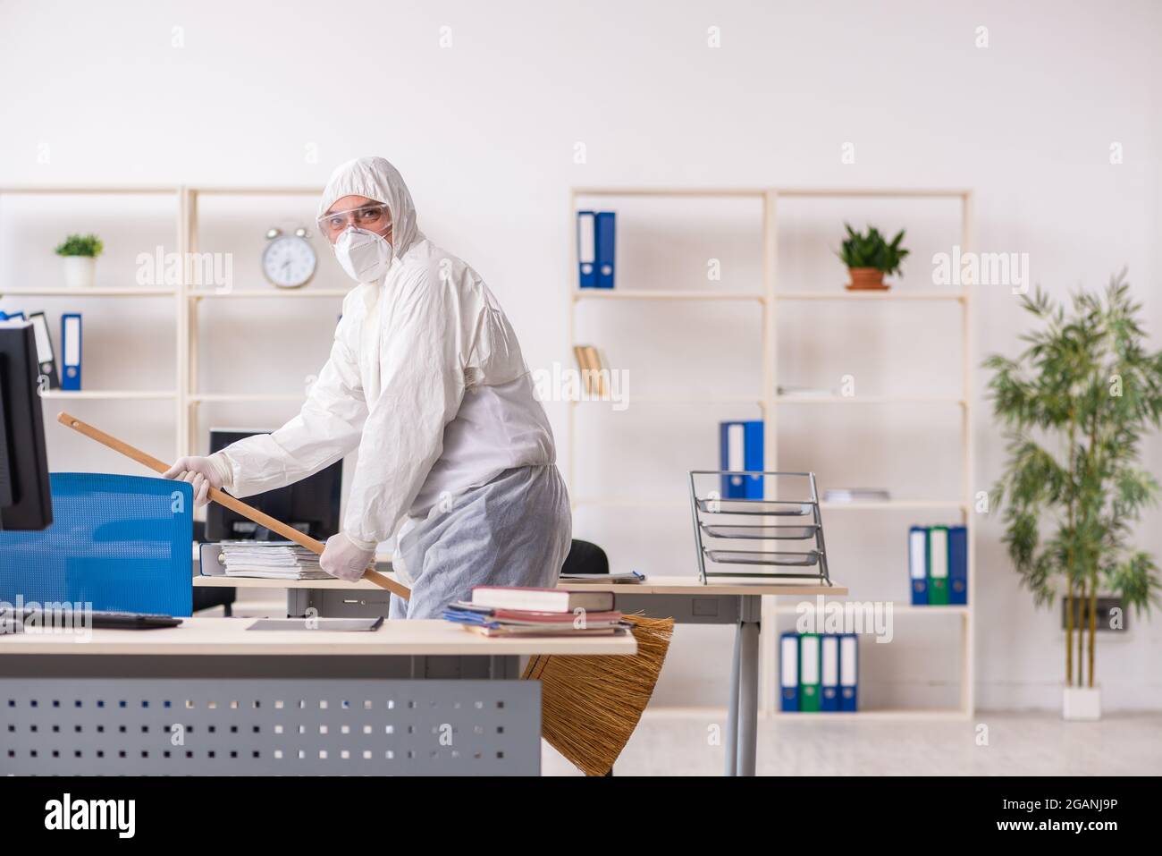 Old contractor cleaning the office holding broom Stock Photo - Alamy