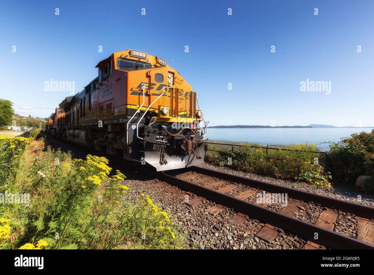 A freight train riding through the city by the beach Stock Photo - Alamy