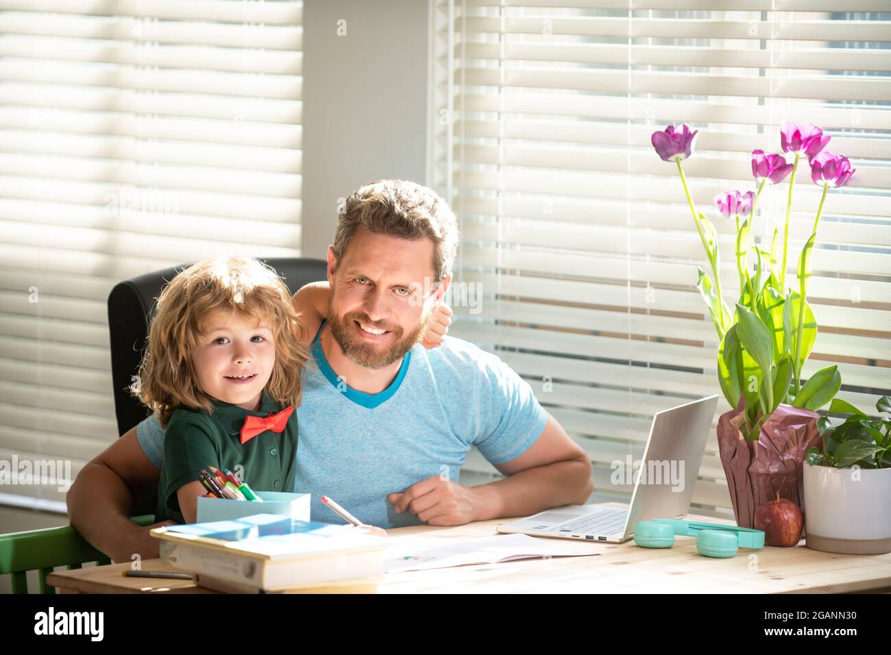 happy father helping his school child study with writing and laptop ...