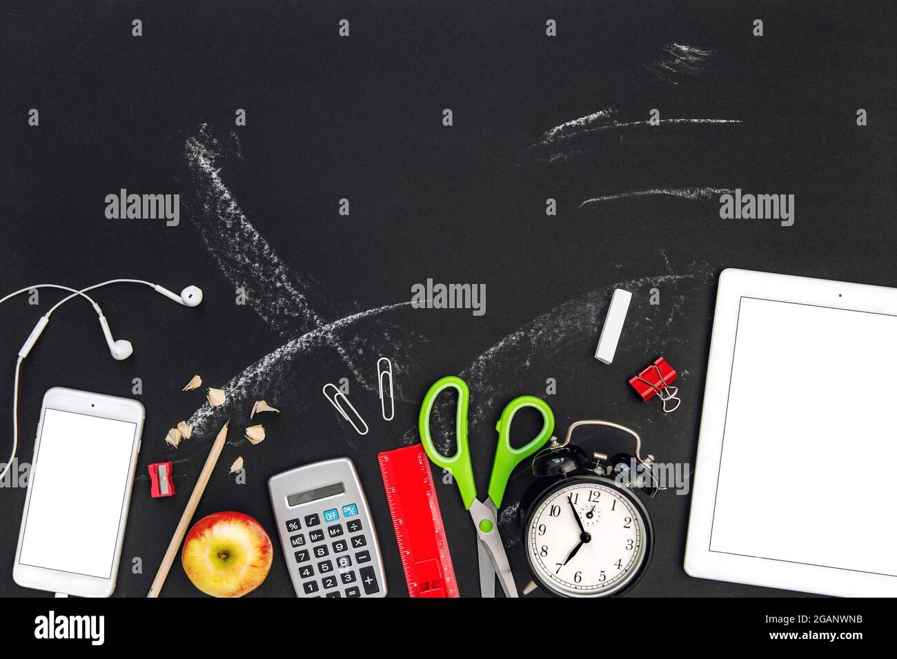 Office supplies and digital gadgets on black chalkboard background ...