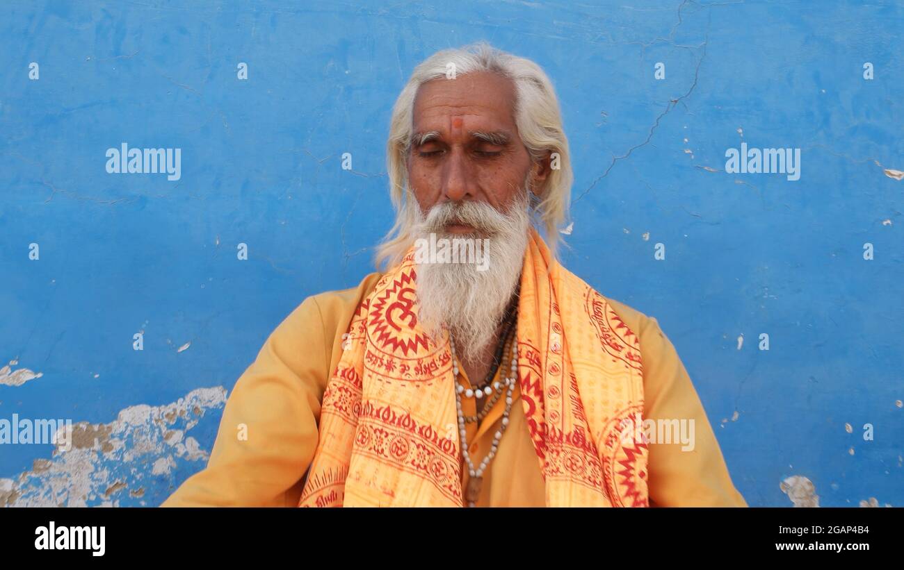 A religious ascetic Sadhu in traditional Indian clothes sitting outdoor ...