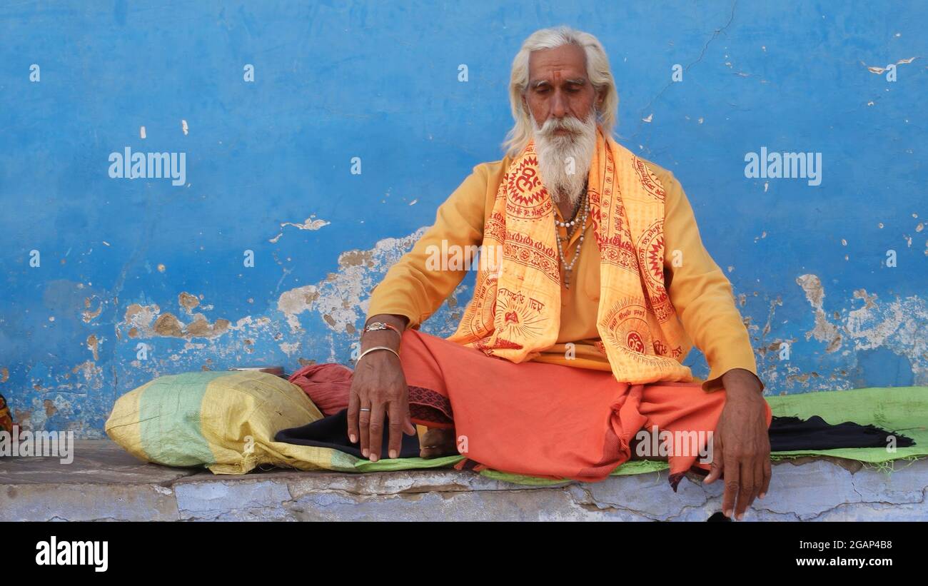 A religious ascetic Sadhu in traditional Indian clothes sitting outdoor ...